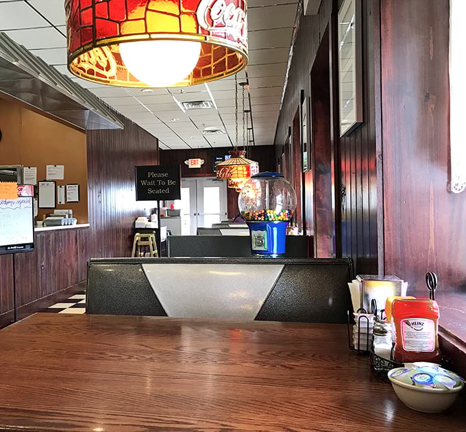Vintage Coca-Cola lamps cast a warm glow over wood-paneled walls that have absorbed decades of laughter, gossip, and the aroma of fresh coffee.