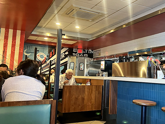 Inside Sip & Bite, the bustling counter and blue tile work create that perfect diner atmosphere where strangers become friends over coffee refills and shared condiments.