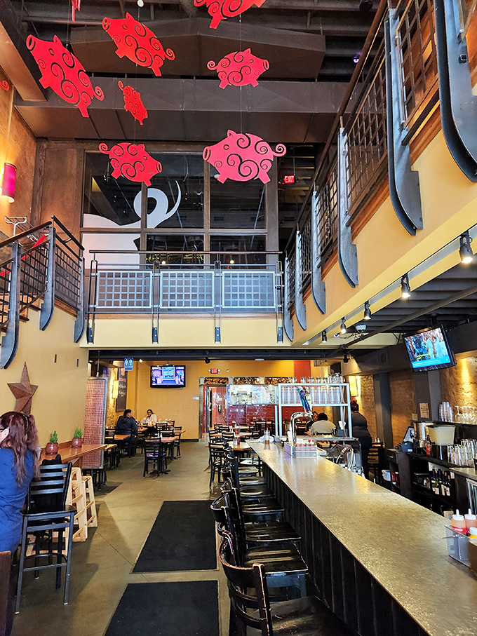 Whimsical red pig cutouts dance overhead in the two-story space where industrial chic meets Southern comfort &ndash; a perfect urban setting for BBQ indulgence.