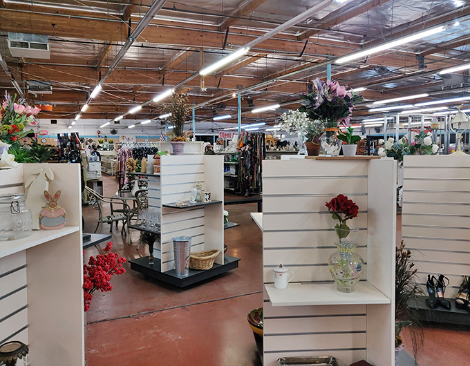 White display shelves showcase delicate vases and floral arrangements, creating an unexpected oasis of elegance amid the thrifting wilderness.