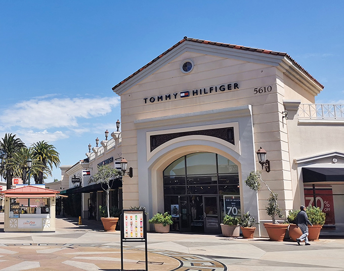 Tommy Hilfiger's crisp white fa&ccedil;ade stands like a beacon of preppy paradise, with those iconic 70% off signs that make your wallet do a happy dance.
