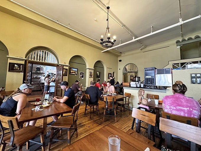 High ceilings, arched windows, and wooden tables create that perfect "third place" where strangers become neighbors over coffee and conversation.