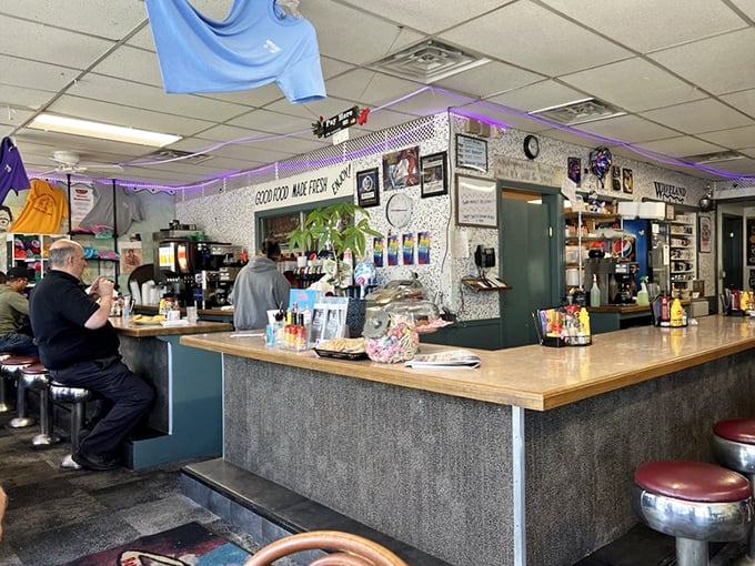 The heart of breakfast operations&mdash;Waveland's counter where coffee flows freely and regulars exchange morning banter. Those purple string lights add just the right touch of diner whimsy.