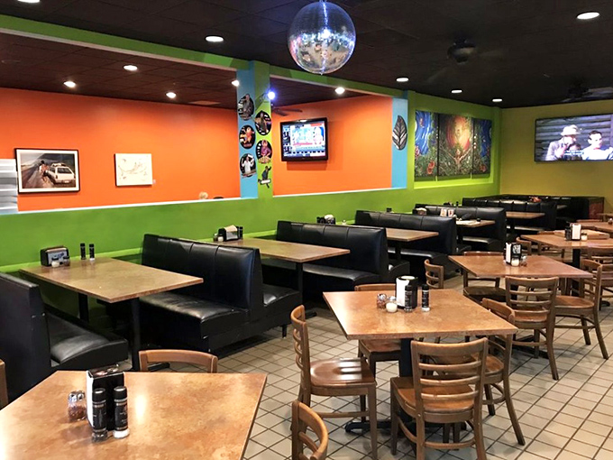 The vibrant interior pops with orange and green walls, where black booths and wooden tables create the perfect stage for pizza performances.