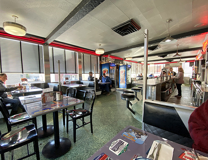 Classic diner geometry: counter seating for solo diners seeking conversation, booths for those with stories to share, all under the warm glow of pendant lights.