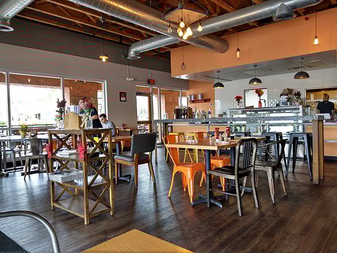 Industrial chic meets cozy comfort in this airy space where Edison bulbs cast a warm glow over mismatched chairs that somehow work perfectly together.