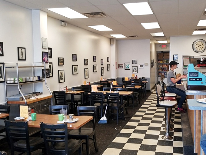 Classic black and white checkered floors, simple wooden tables, and walls adorned with photos—this is diner perfection without pretension.