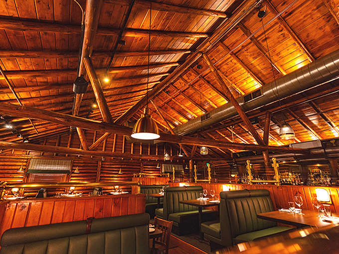 Beneath honey-colored wooden beams that soar overhead, the dining room glows with amber warmth that makes everyone look like they've discovered the fountain of youth.