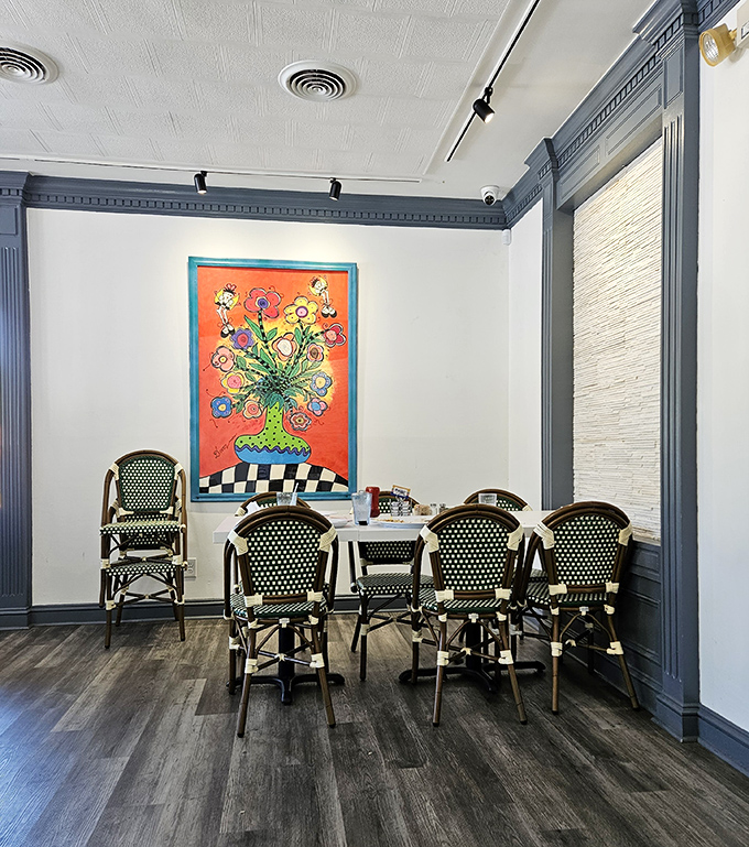 A vibrant pop-art floral painting brings cheerful energy to this cozy dining nook, where bistro chairs invite you to settle in for a leisurely breakfast worth savoring.