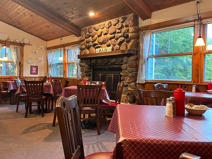 A stone fireplace anchors the dining room, where red checkered tablecloths and wooden chairs whisper, "Slow down, stay awhile."
