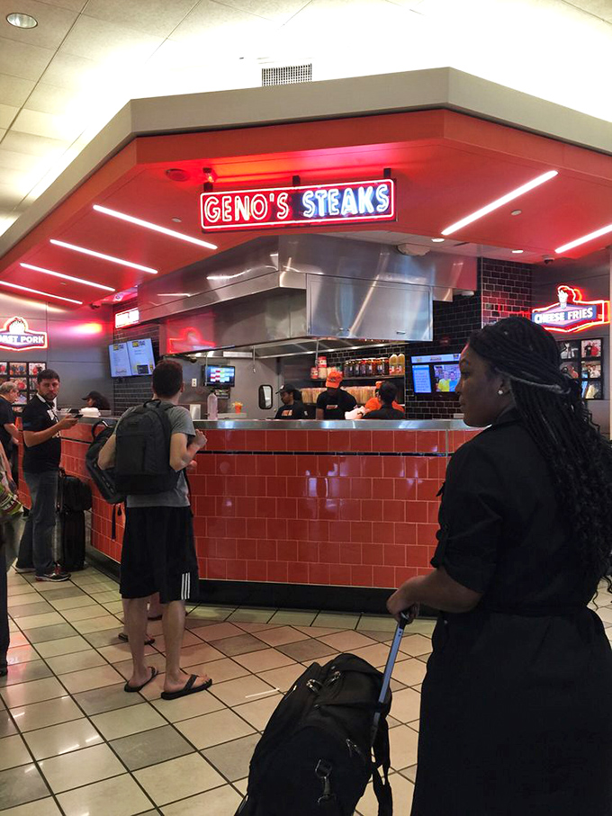 Inside Geno's airport location, the signature orange and red glow creates the same electric atmosphere as the original. Even travelers can't escape Philly's cheesesteak gravitational pull.
