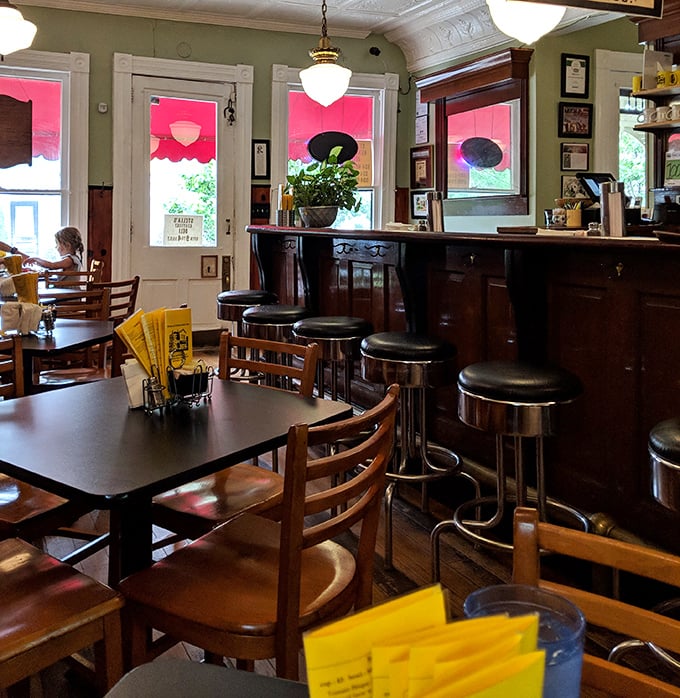 Inside, wooden tables, vintage bar stools, and soft green walls create the perfect backdrop for food conversations that inevitably begin with "You have to try this!"