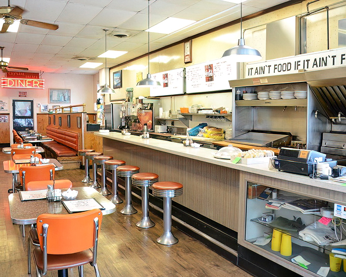 Classic counter seating where regulars perch like they own the place, beneath that perfect diner motto: "It Ain't Food If It Ain't Fried."