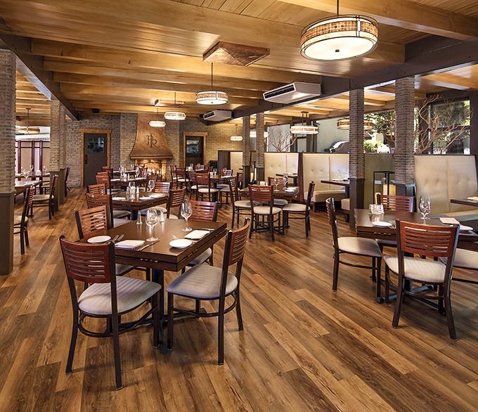 Warm wood tones, brick accents, and perfectly spaced tables create that rare dining atmosphere where conversation flows as smoothly as the wine.