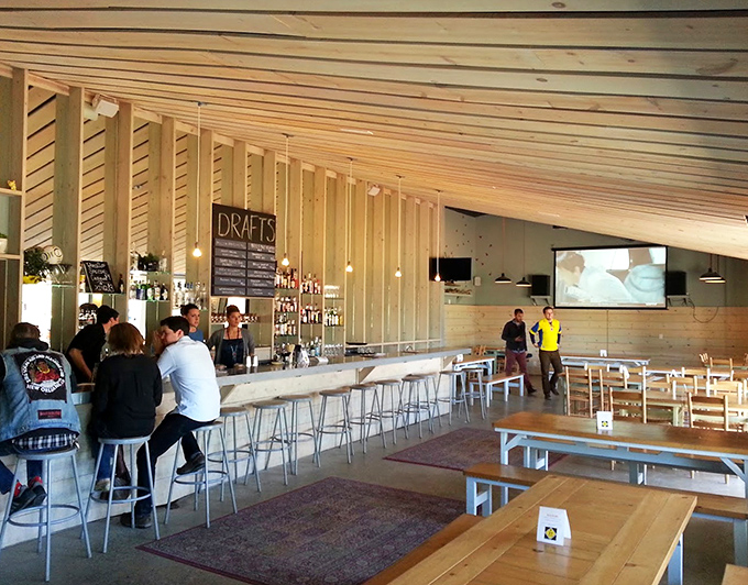 Inside, wooden slat walls and minimalist design create a space that's both modern and welcoming, where the bar becomes the heart of the gathering.