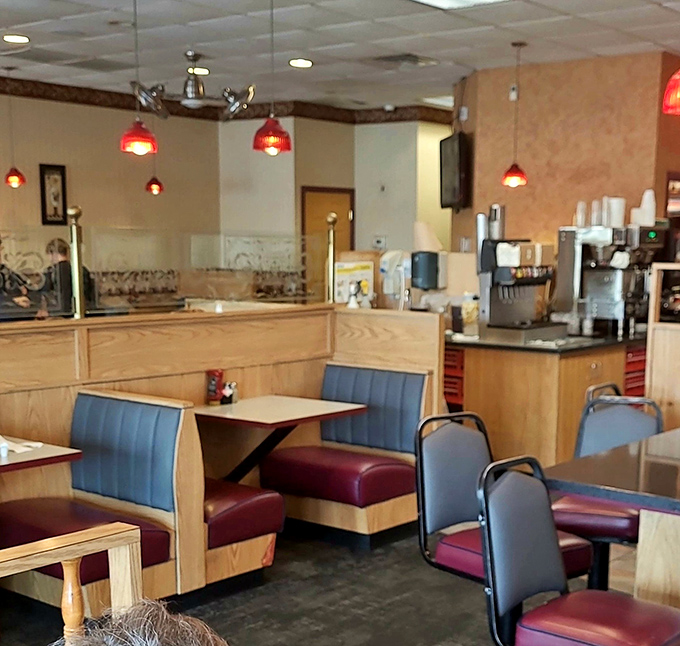 Classic diner comfort in burgundy and wood. Those red pendant lights cast the kind of glow that makes everyone look like they're having the best day ever.