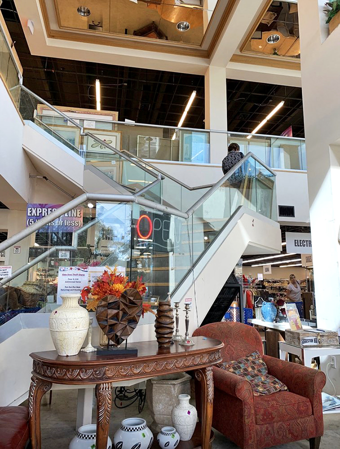 A grand staircase worthy of a department store leads to more bargains above. That ornate console table and armchair? Just appetizers for the feast of finds within.