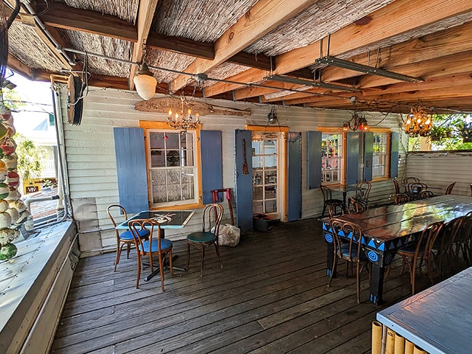 Rustic charm meets island tranquility on this covered porch, where weathered wood and blue shutters create the perfect backdrop for unforgettable meals.