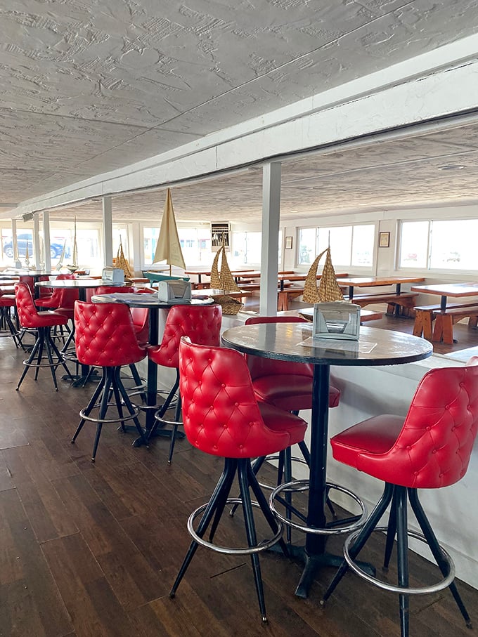 Those vibrant red chairs aren't just for show—they're where the magic happens as you contemplate your feast while model sailboats remind you of your meal's oceanic journey.