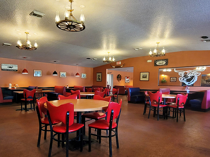 Red chairs pop against orange walls in this no-frills dining room. The wagon wheel chandeliers aren't trying to impress Architectural Digest&mdash;they're saving their energy for your taste buds.