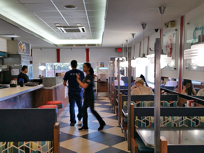 Classic black and white checkered floors set the stage for culinary theater, where servers dance between booths delivering plates that could make a food photographer weep.