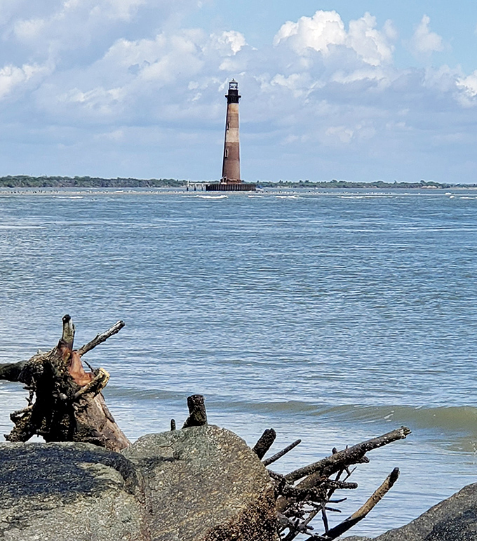 From the beach, the lighthouse appears like a distant chess piece on a vast blue board, patiently waiting for its next move.