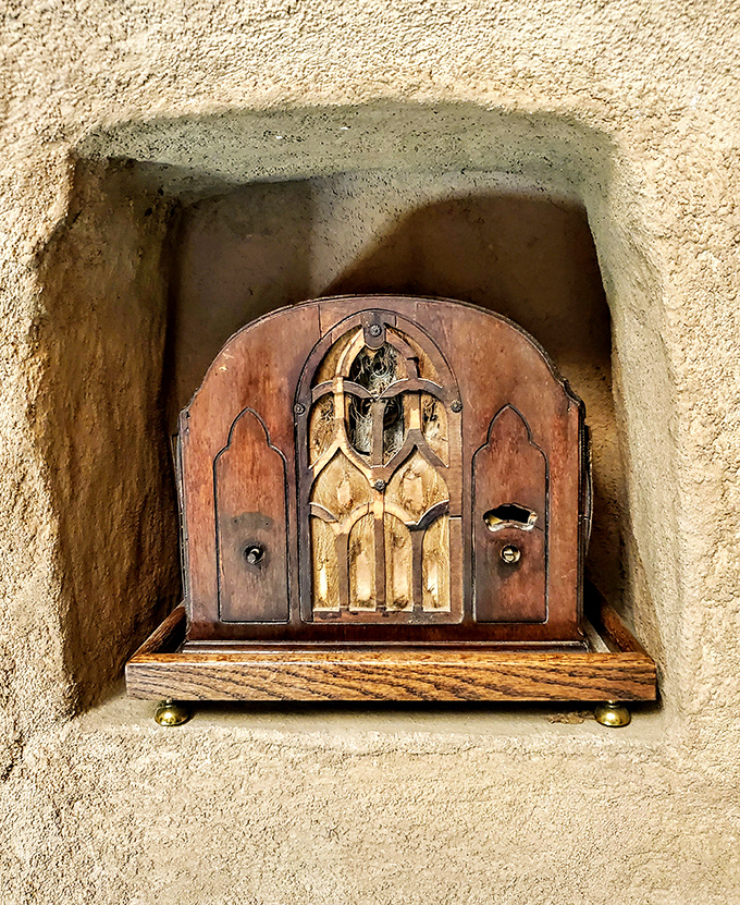 This vintage radio sits tucked into the earthen walls, a reminder that entertainment once meant gathering around beautiful wood.
