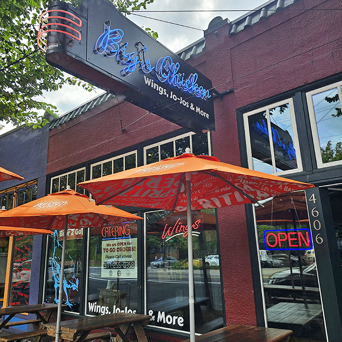 Big's Chicken's vibrant blue rooster sign watches over sidewalk diners enjoying smoky, crispy perfection under cheerful umbrellas.