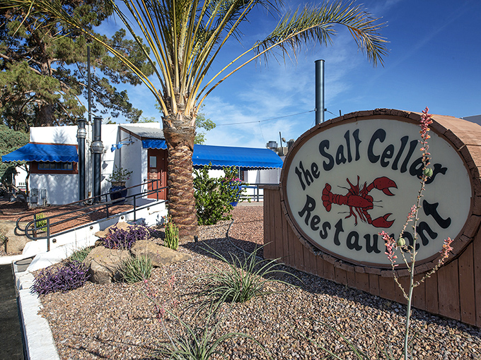 The Salt Cellar's charming sign and palm tree welcome you to a subterranean seafood adventure in Scottsdale.