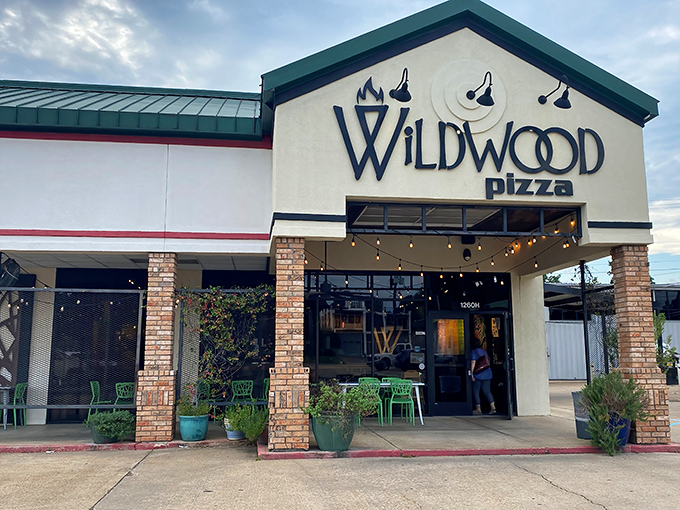 Wildwood Pizza's welcoming storefront promises rustic comfort. Those green chairs aren't just seating&mdash;they're invitations to linger over one more slice.