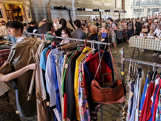 Colorful clothing racks stretch endlessly under historic bridges - fashion archaeology at its finest.