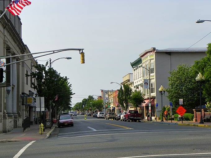 Sunlight bathes Millville's main street, where American flags wave and shop owners still remember your name.