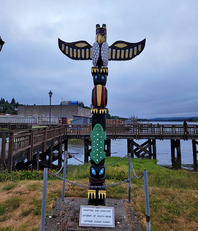 The totem pole stands sentinel over the waterfront, adding traditional Pacific Northwest artistry to the oyster festivities.