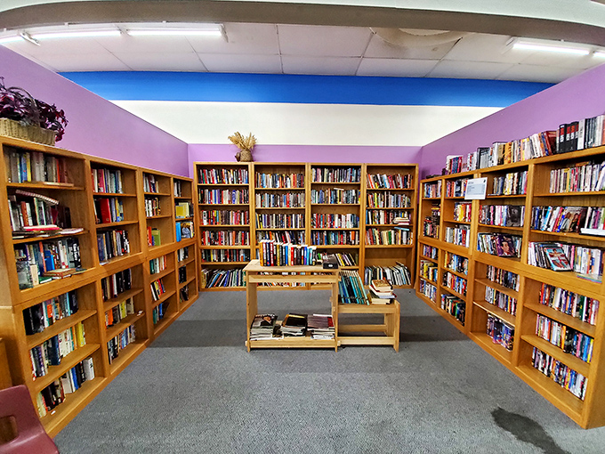 The literary nook where bookworms can feast without breaking the bank. Purple walls frame wooden shelves holding thousands of stories waiting for their next chapter.