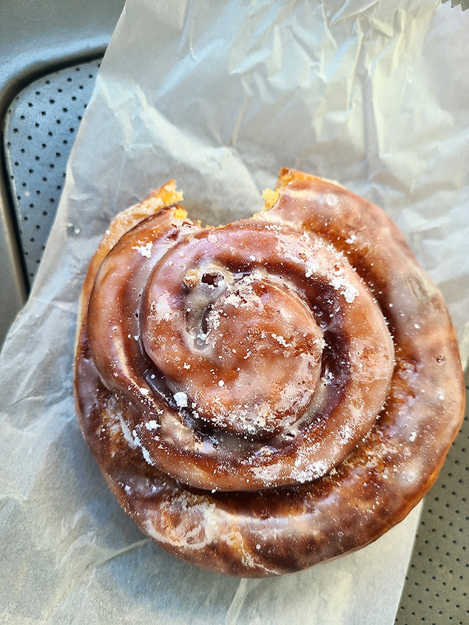 Behold the cinnamon roll in its natural habitat: glistening with glaze, spiraled to perfection, and absolutely worth the drive.