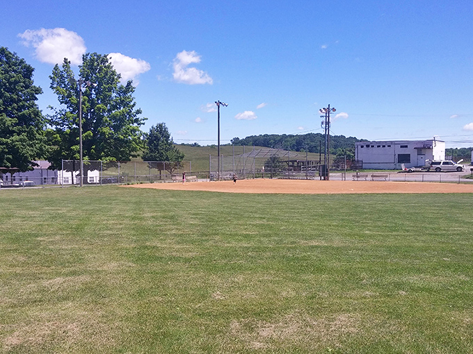 Simple pleasures await at the local ballfield, where community games unfold beneath blue skies and the distant embrace of rolling hills.