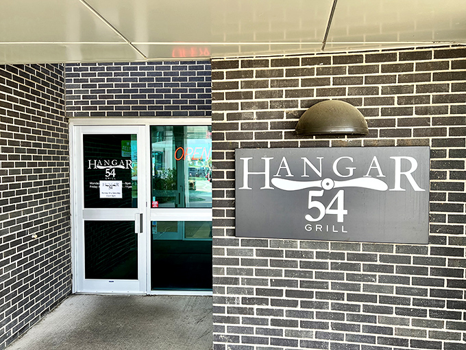 Hangar 54 Grill's sleek brick exterior promises aviation-themed dining where the only thing more satisfying than watching planes take off is biting into their legendary burgers.