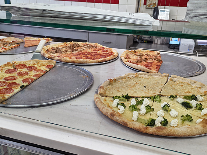 Pizza perfection on display—from classic pepperoni to white broccoli specialties, each pie awaits its moment to shine under the warming lights.