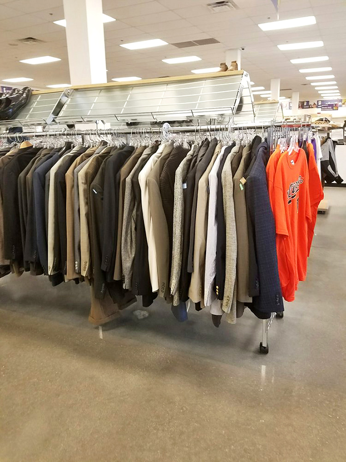 Men's suits and sport coats hang like patient sentinels, including that bright orange shirt boldly declaring "I'm not like the others!"
