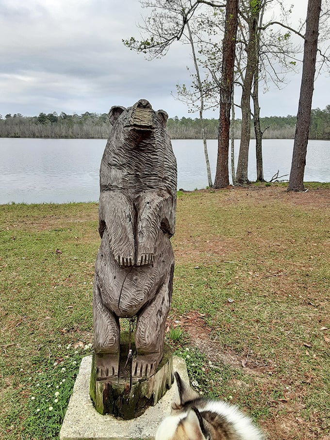 This wooden bear sculpture stands sentinel by the lake, silently judging your fishing skills while offering the perfect photo op for visitors since... well, forever.