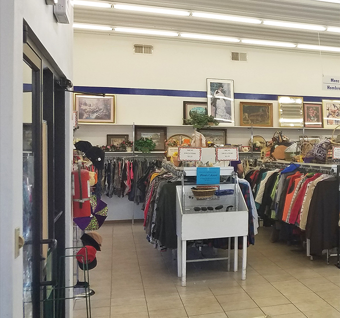 The art gallery of everyday life hangs above racks of clothing, where framed memories find new homes alongside gently-used fashion statements.
