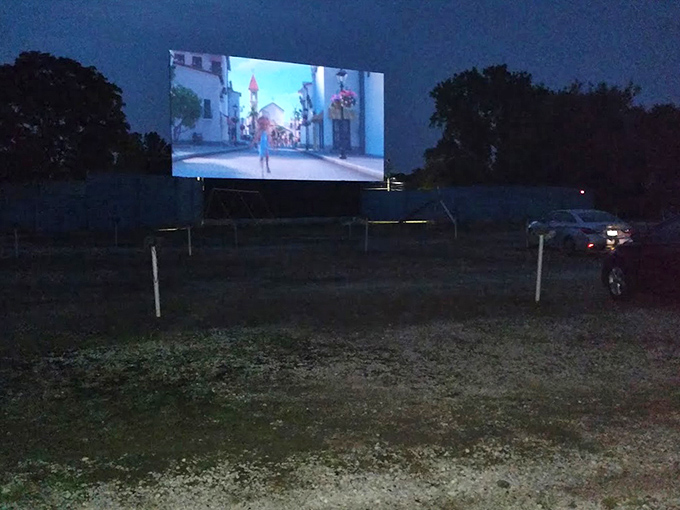 Movie magic under the stars! The film dances across the screen while cars nestle together like old friends sharing secrets.