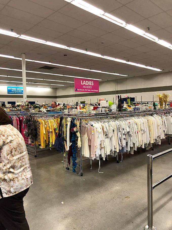 Under the pink "Ladies" sign, a rainbow of blouses and dresses stands ready for their second act.