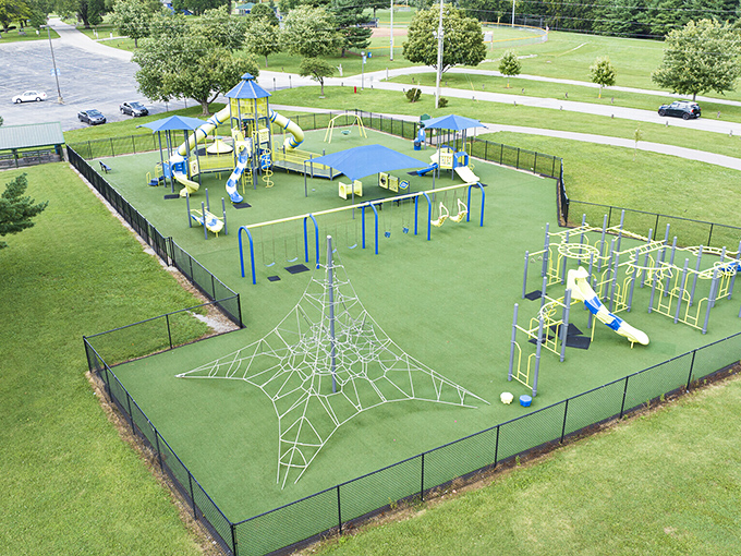 This playground isn't just for kids! Retirees gather on nearby benches to enjoy Kentucky's blue skies while grandchildren conquer the spider web climbing structure.
