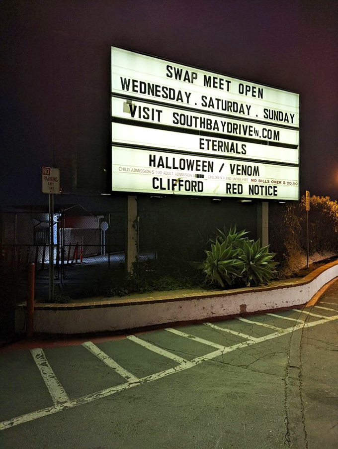 The illuminated marquee announces the night's features, a glowing beacon of entertainment that feels delightfully retro in our digital age.