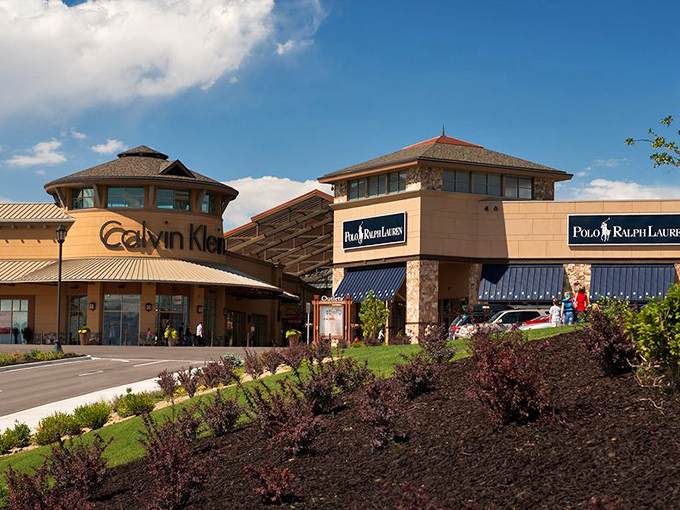 Calvin Klein's architectural presence dominates the scene, proving minimalist design works even when describing outlet mall real estate.