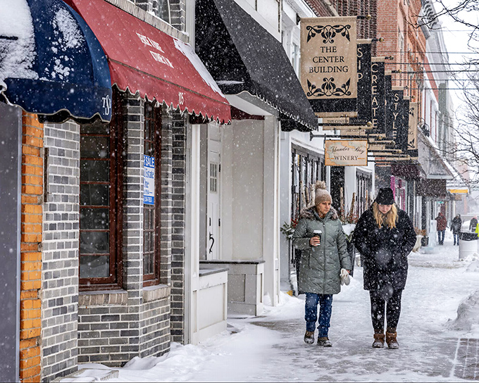Two friends brave a snowfall on Second Avenue, coffee in hand. In Alpena, winter isn't endured&mdash;it's embraced with good company.