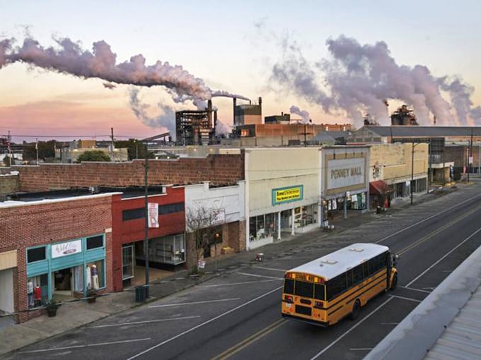 A yellow school bus cruises past storefronts that have weathered decades with Southern grace and dignity.