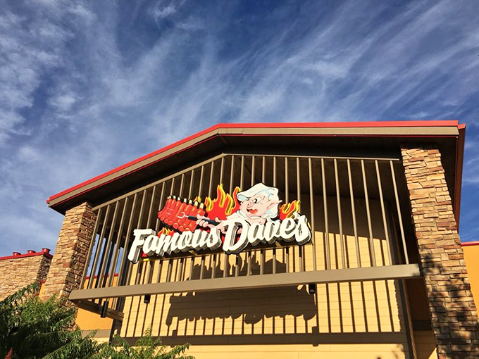 Famous Dave's neon pig sign glows like a BBQ beacon against the blue sky. This is where smoke meets meat in perfect harmony.