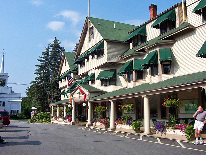 Step into a postcard moment where this classic red covered bridge frames mountain views like a master photographer's lens.